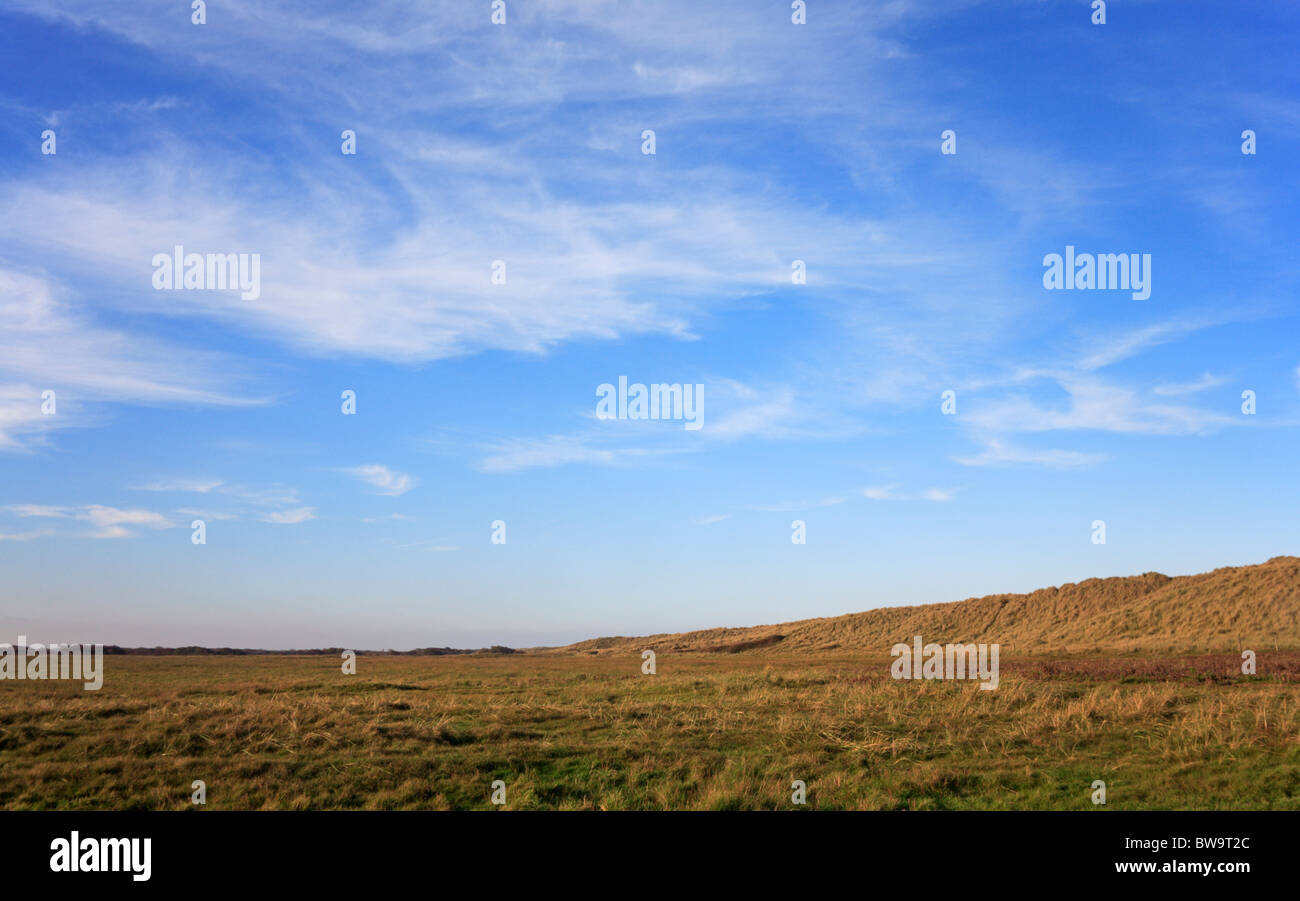 A landscape of sand dunes and grazing marsh with cirrus clouds at ...