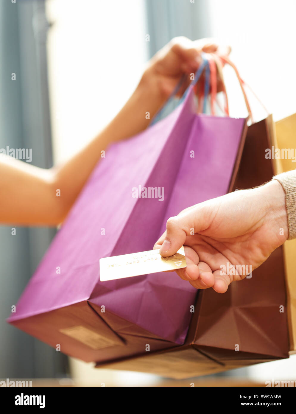 Vertical image of man’s hand passing over credit card to shop assistant ...