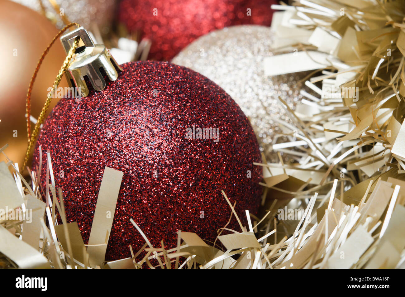 Red, silver and gold Christmas baubles nestling in gold tinsel ...