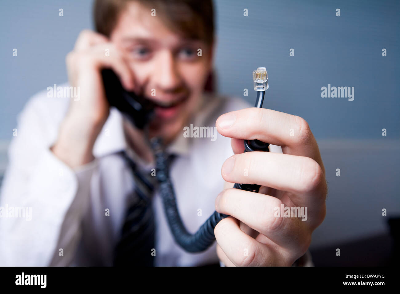 Unplugged wire of telephone in human’s hand on background of ...