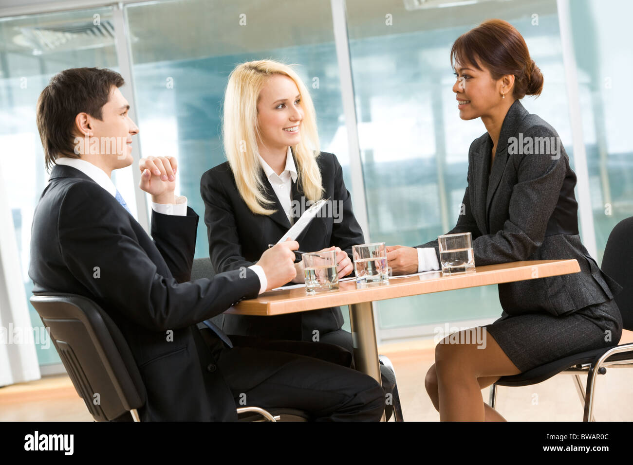 Photo of successful employees gathered around table explaining their ...