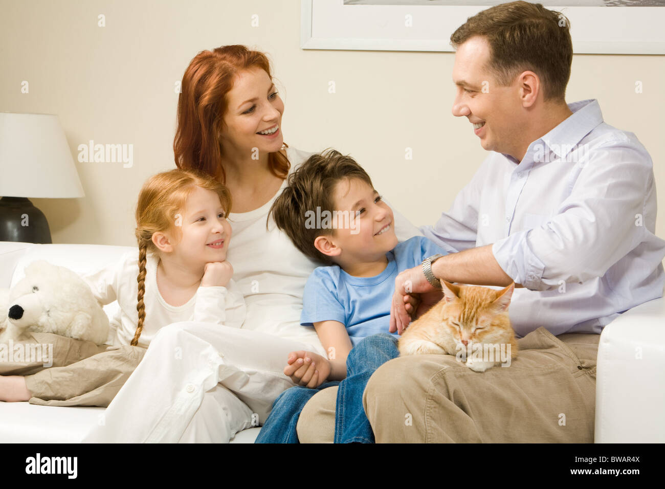 Friendly family members sitting on comfortable sofa and communicating ...