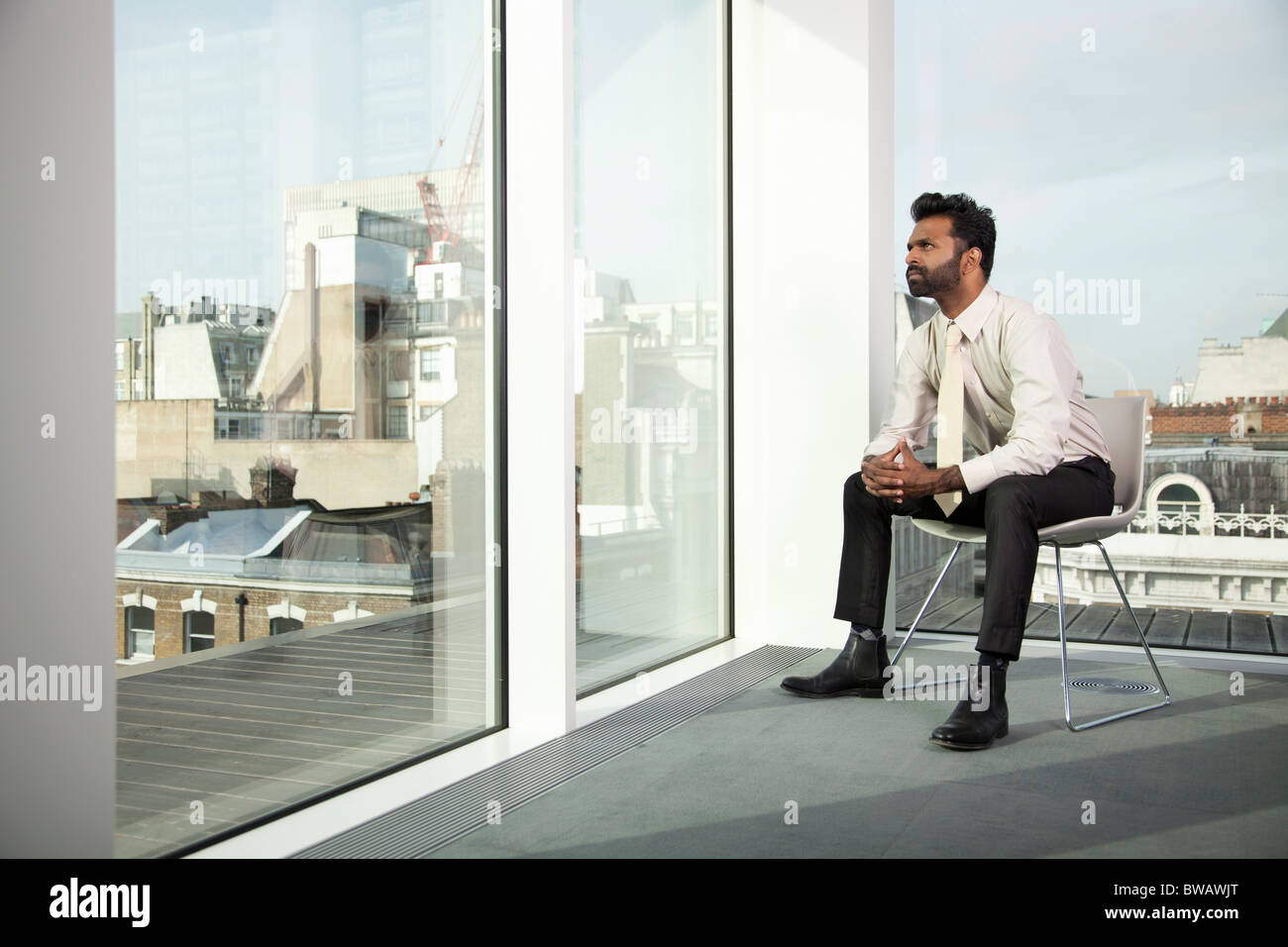 Businessman looking out of office window Stock Photo - Alamy