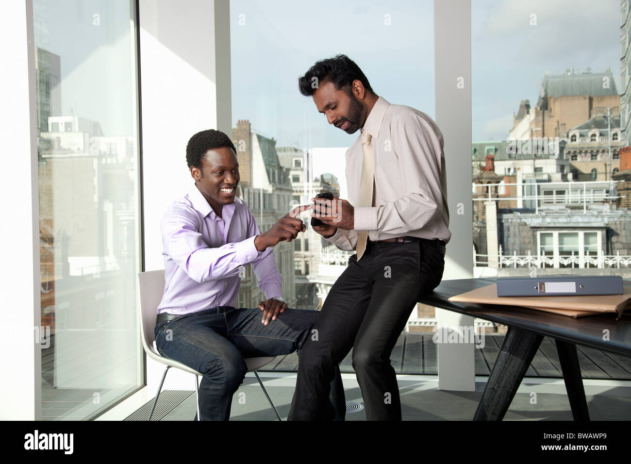 Two men discussing mobile telephone Stock Photo - Alamy