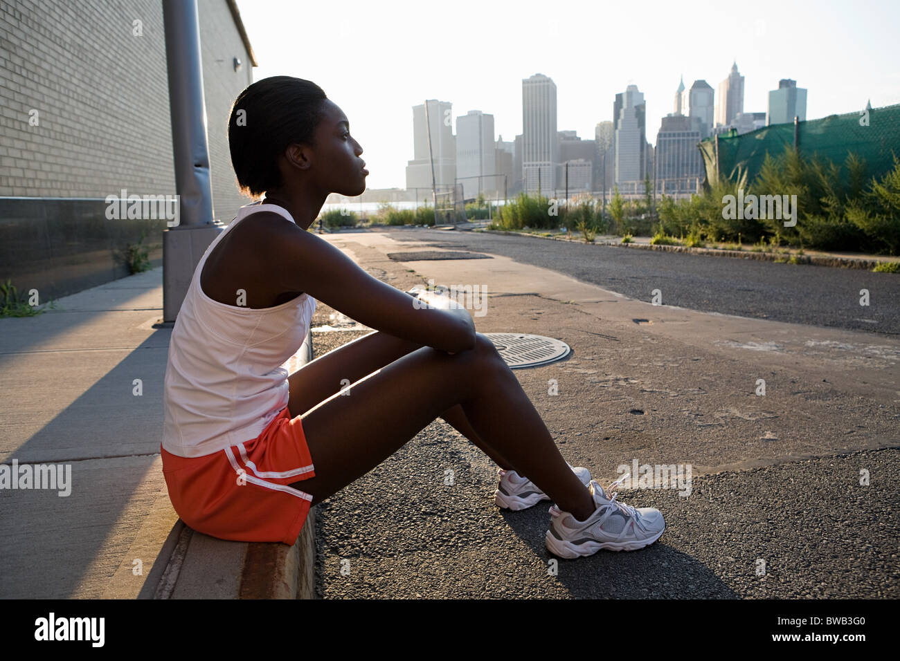 Runner sitting on sidewalk Stock Photo - Alamy