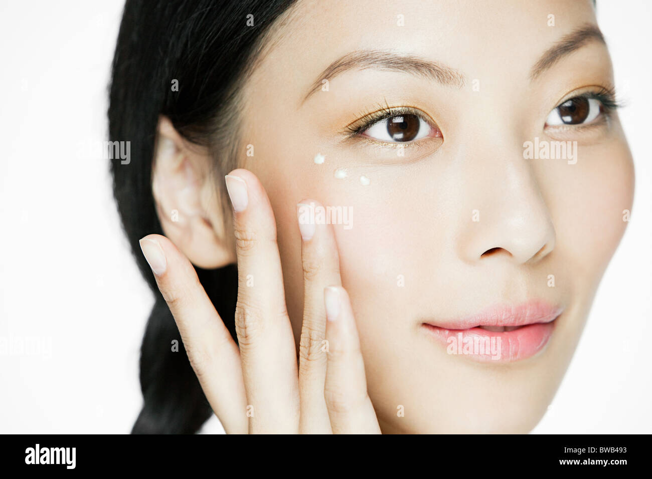 Young woman applying eye cream Stock Photo - Alamy