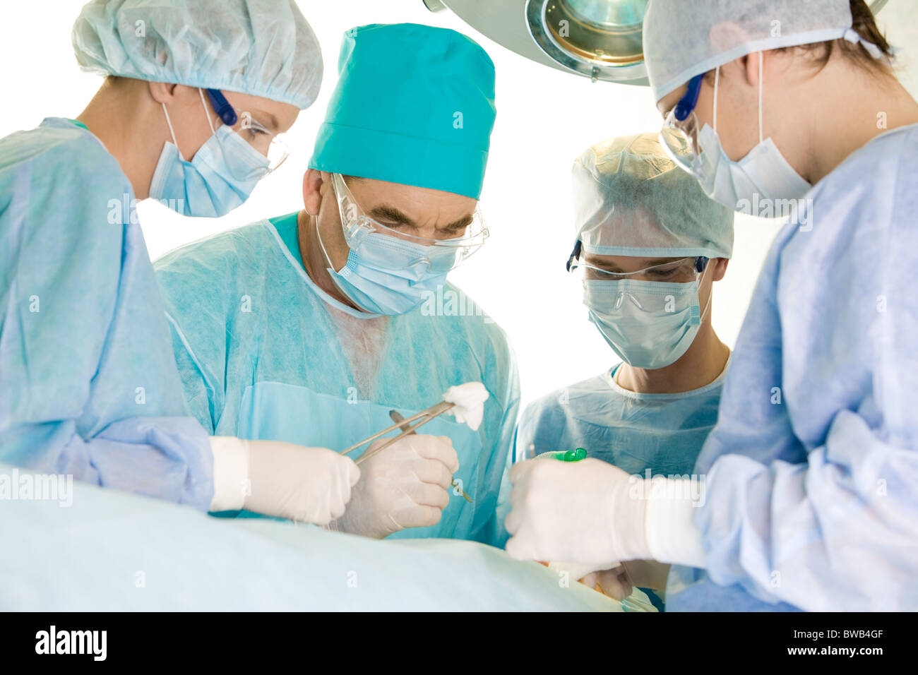 Several surgeons surrounding patient on operation table and looking at ...