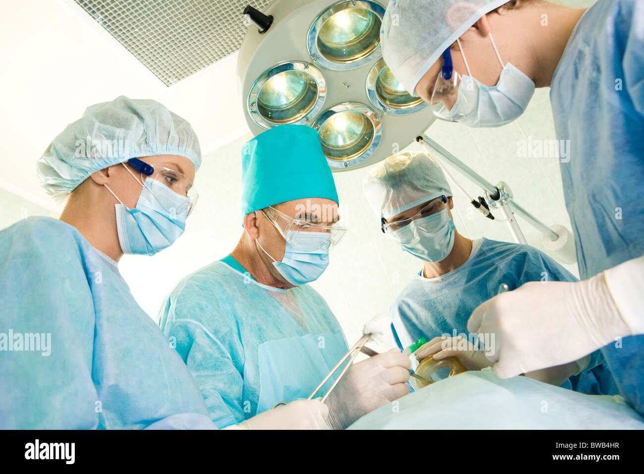 Group of surgeons looking at patient on operation table during their ...