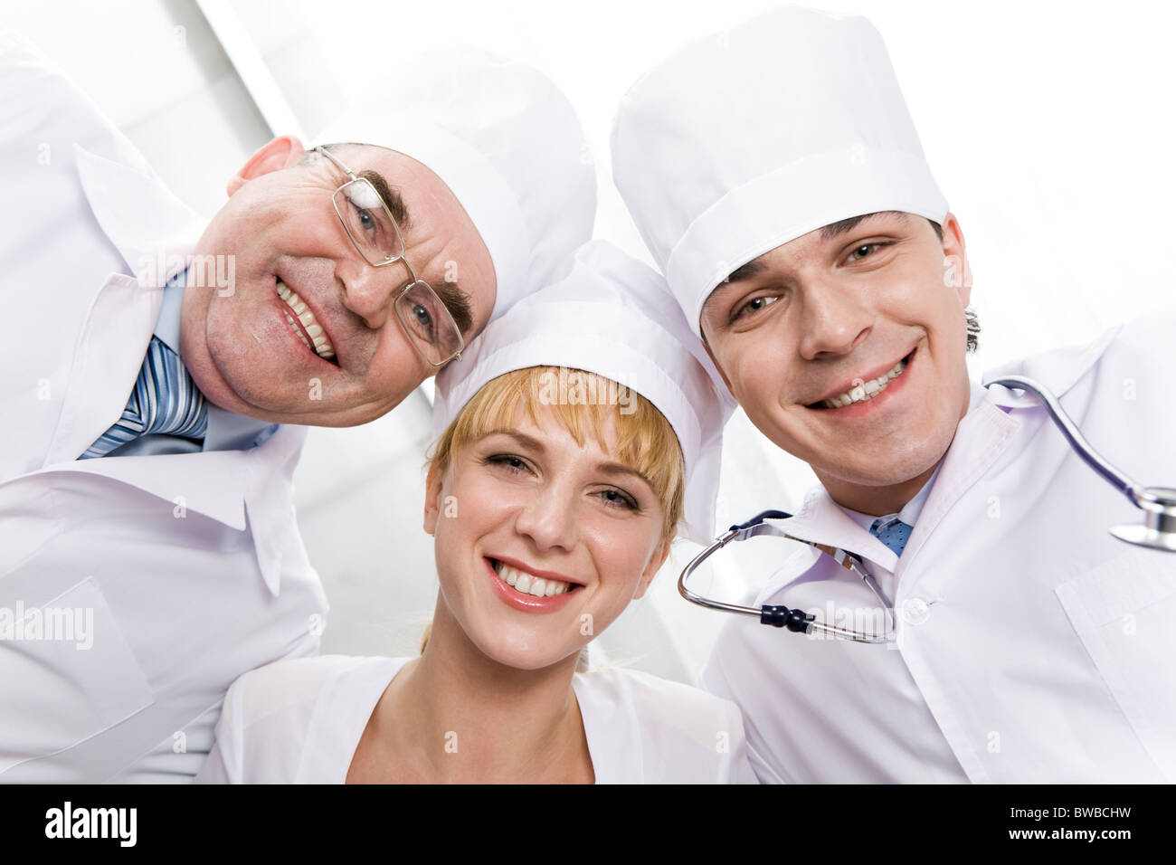 Below view of three practitioners looking at camera with friendly ...