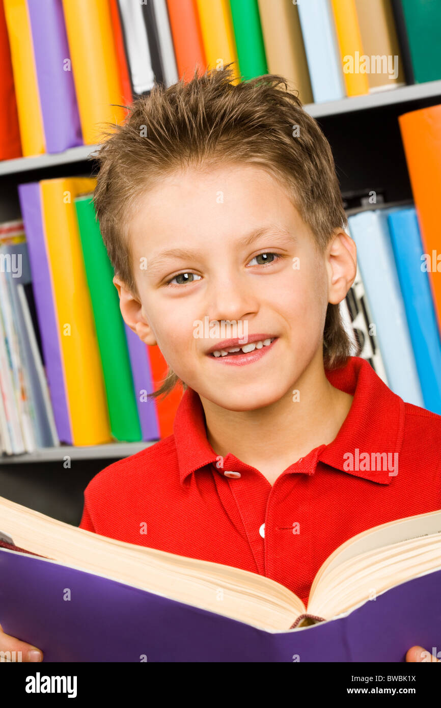 Portrait of smart boy with open book looking at camera and smiling ...