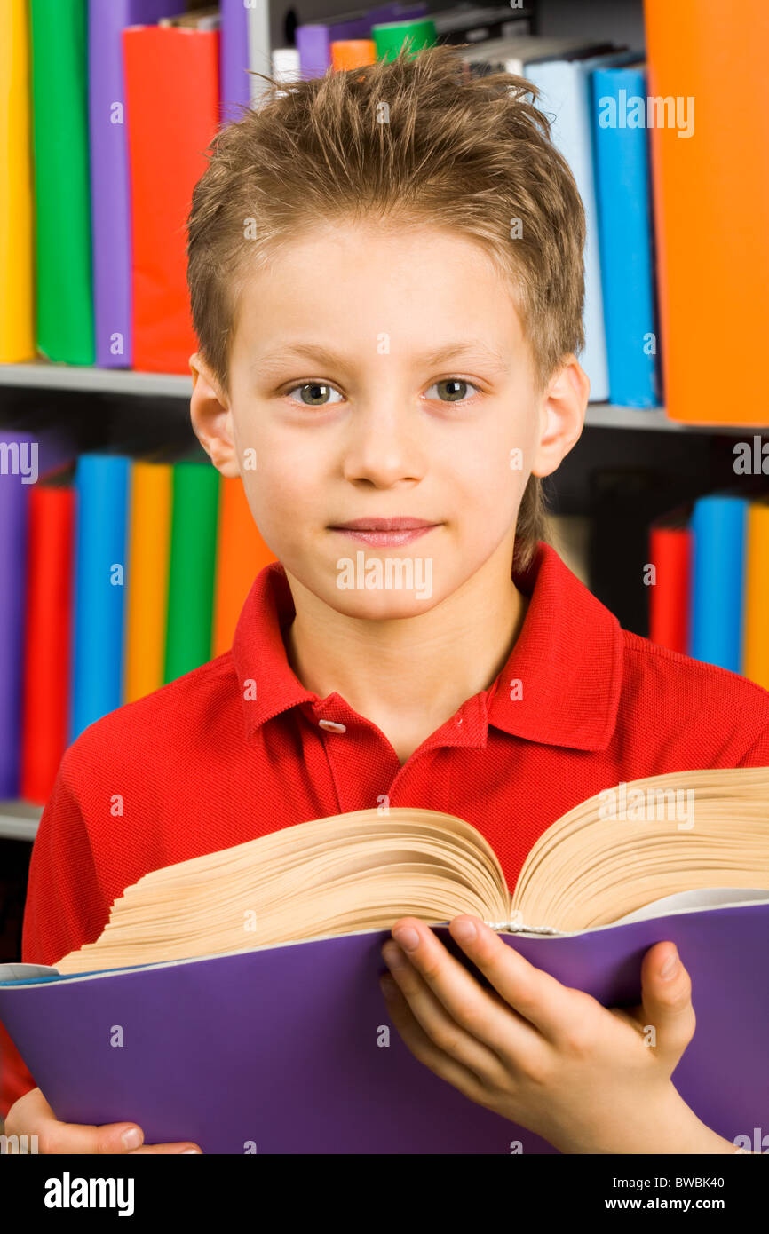 Portrait of smart boy with open book looking at camera in library Stock ...