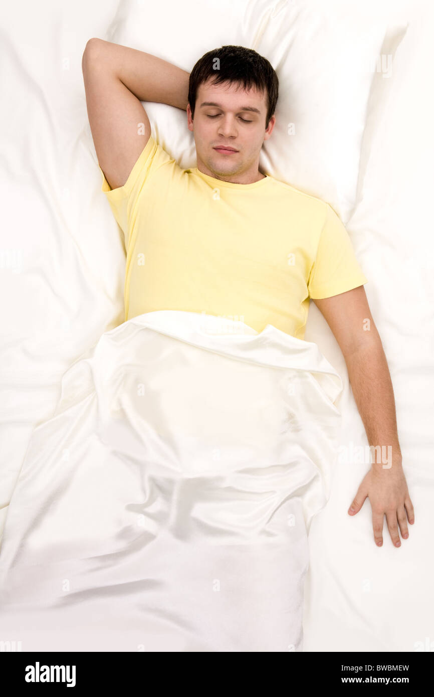 Above view of man with one hand under his head sleeping in cosy bed ...