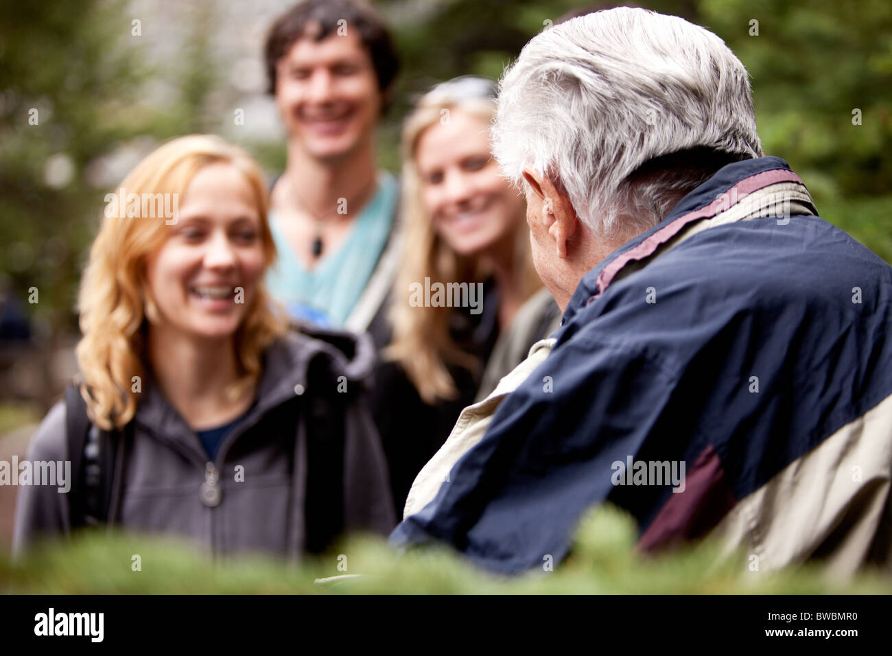 An elderly man talking to a group of young people in the forest Stock ...
