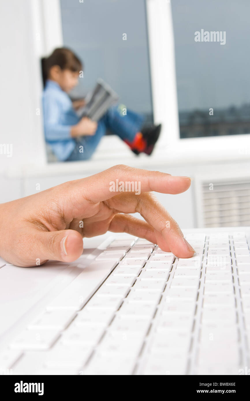 Close-up of female’s hand over keyboard button with a child at ...