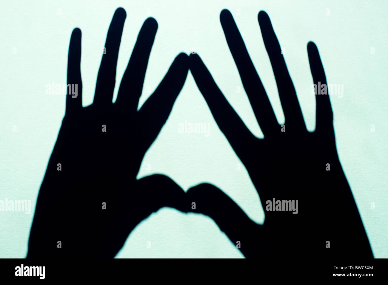 Two hand shadows on light blue background Stock Photo - Alamy