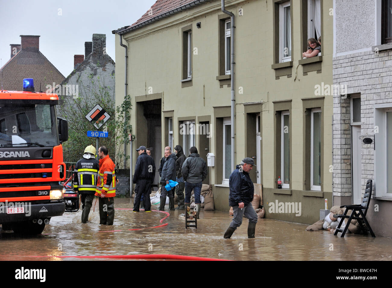 Flooded street and sandbags piled up in front of doors at Nederzwalm ...