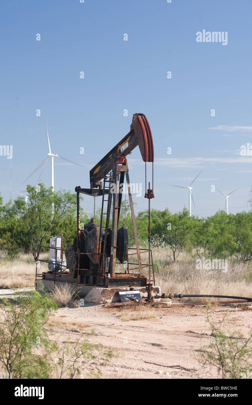 Pumpjack in an oil field adjacent to a wind farm of high-tech wind ...