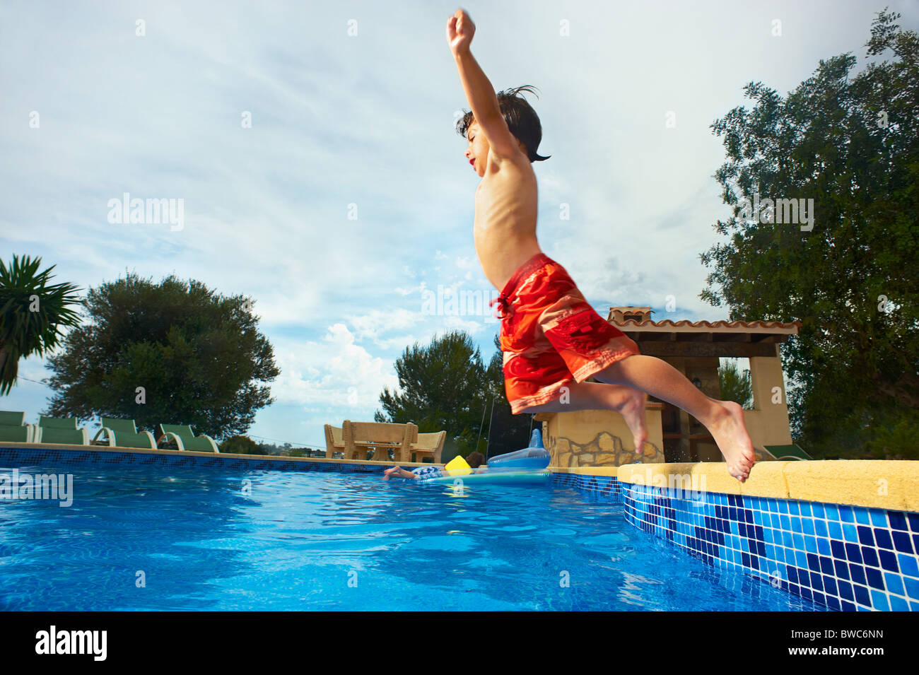 Young boy jumping into swimming pool Stock Photo - Alamy