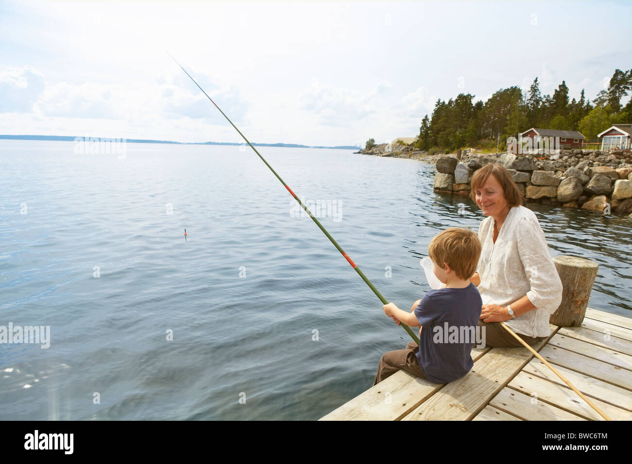 Smiling grandmother watching fishing boy Stock Photo - Alamy