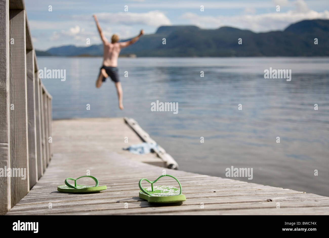 Man jumping off wooden jetty into sea Stock Photo - Alamy