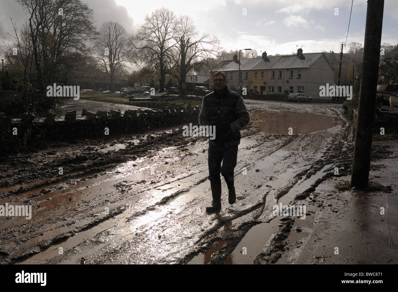 Man walking through mud covered road in Lostwithiel after flash ...