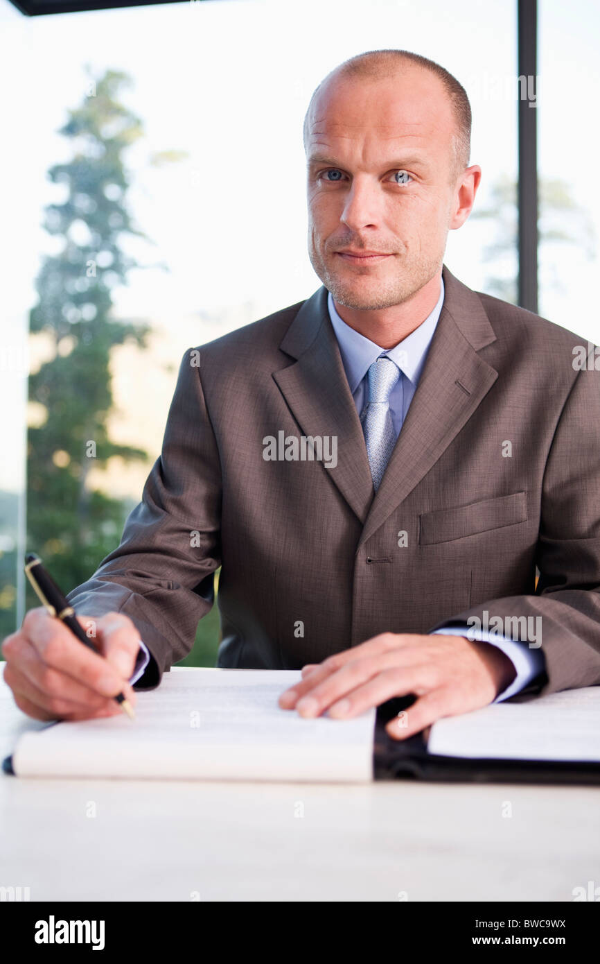 Portrait of mid adult businessman signing document Stock Photo - Alamy