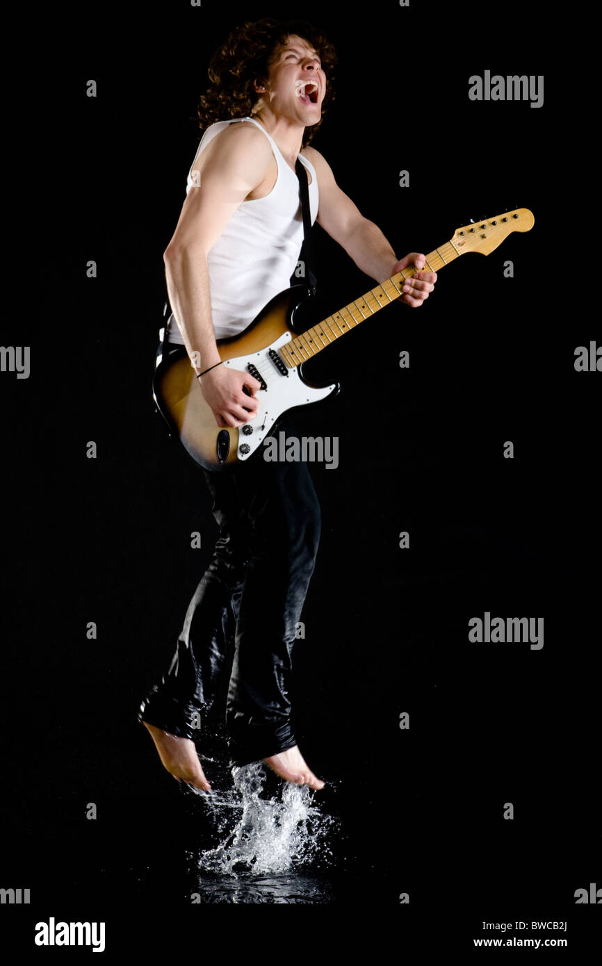 Portrait of dynamic performer playing electrical guitar while jumping ...