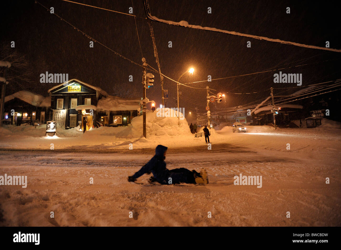 A man slides on his snowboard down the main street in Hirafu, a village ...