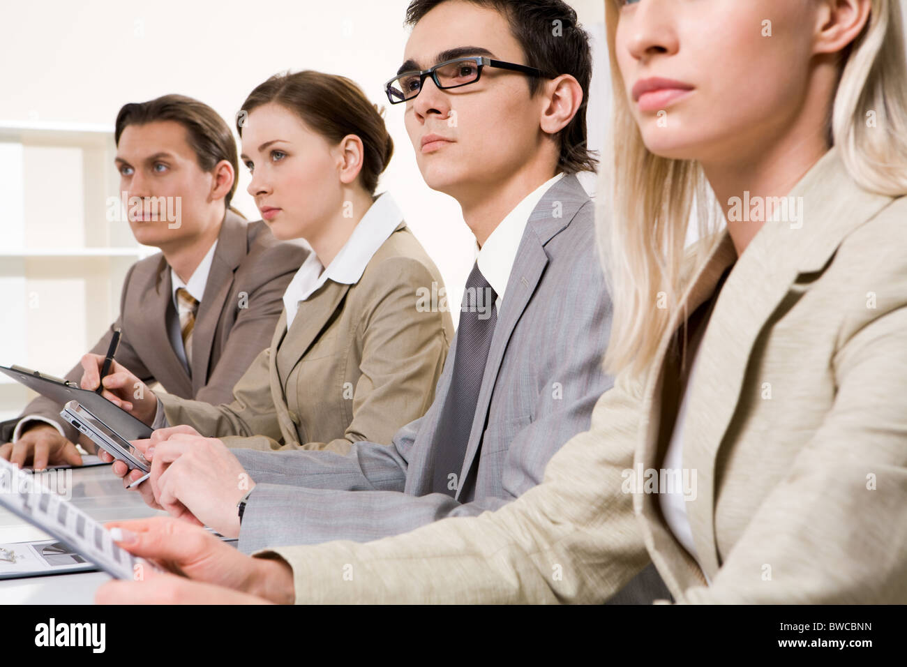 Serious students sitting in row and looking at board during ...