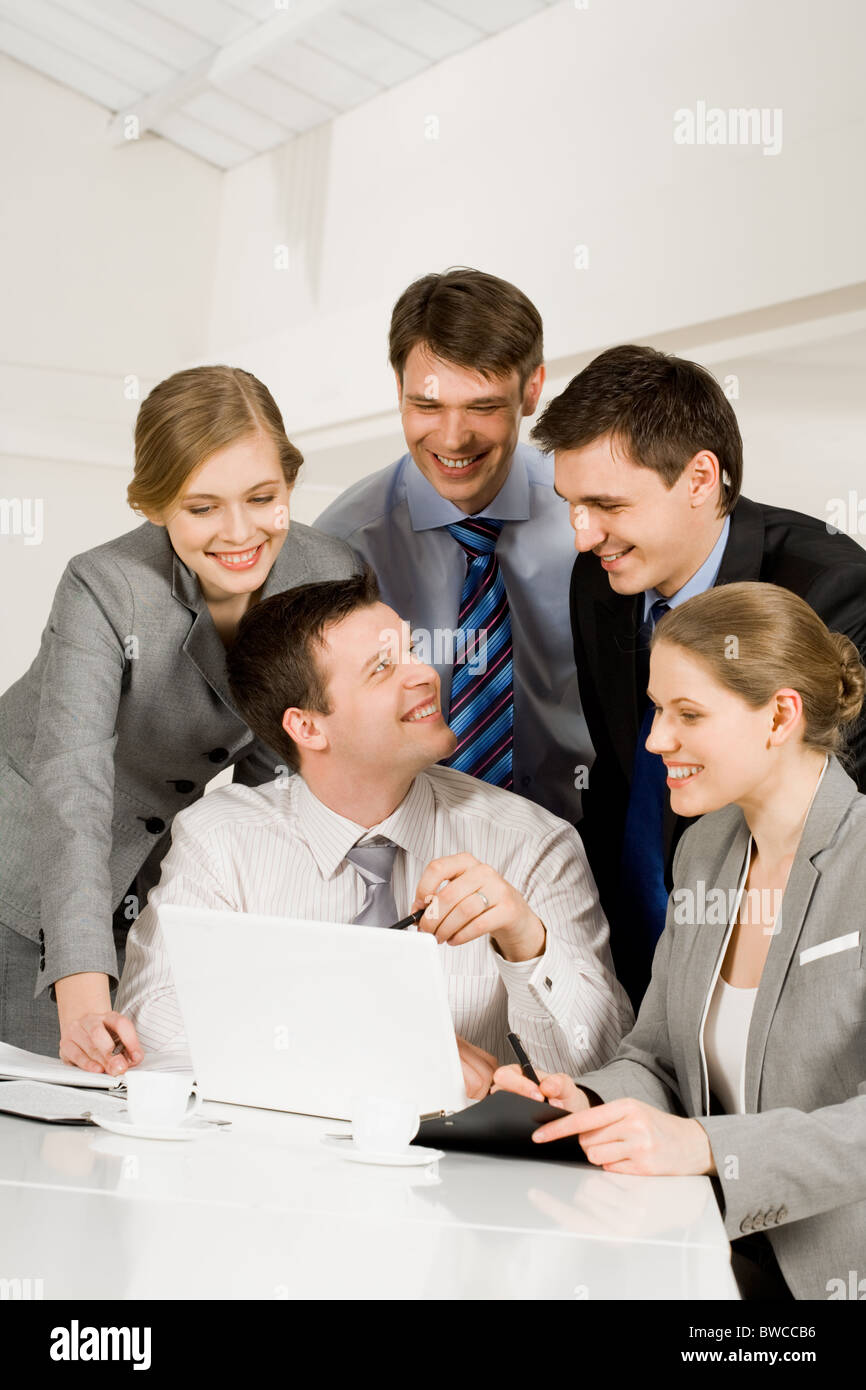 Portrait of successful employees looking at laptop monitor while ...