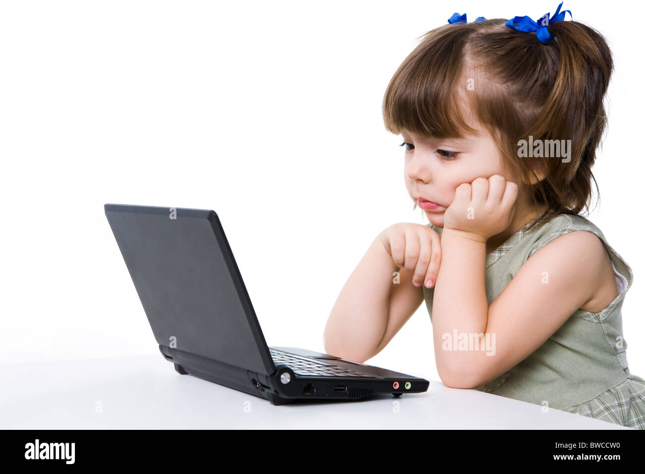 Portrait of elementary school girl looking at laptop screen with ...