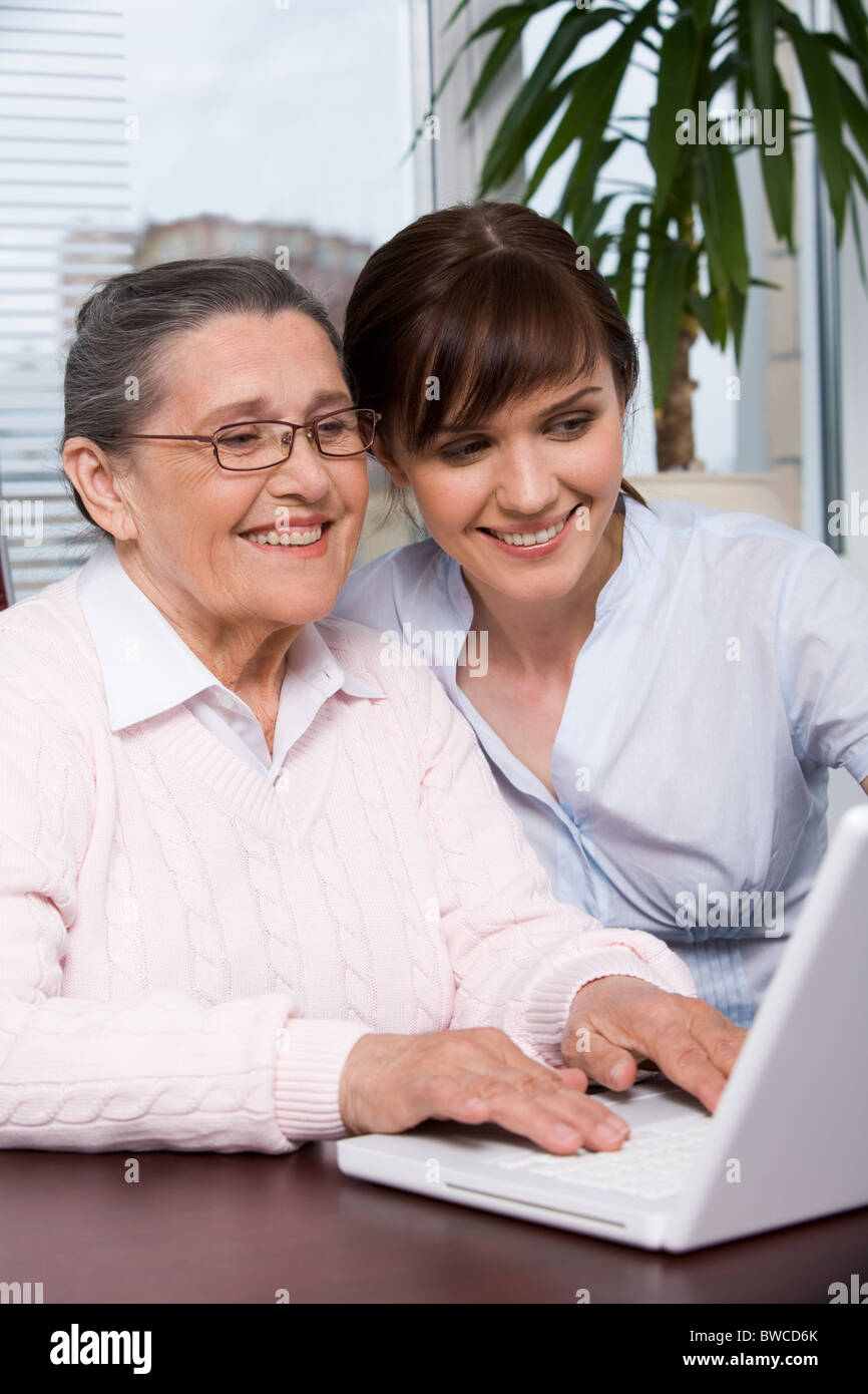 Portrait of young girl and her grandmother looking at laptop screen ...