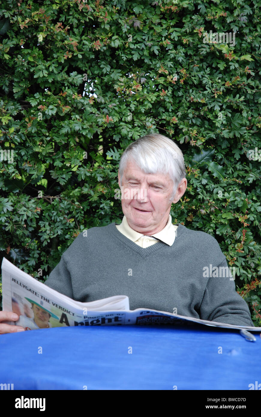 OAP man sitting outdoors reading a newspaper Stock Photo - Alamy