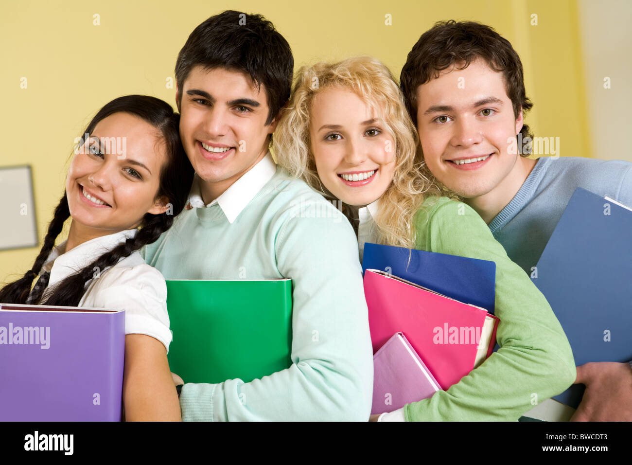 Portrait of happy students standing close to each other and looking at ...