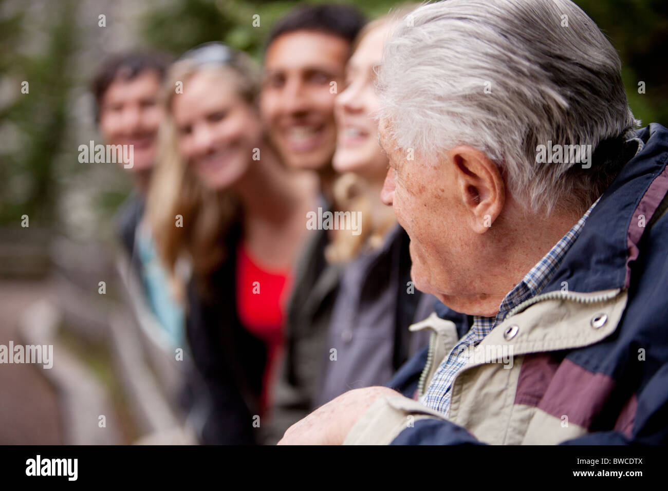 An elderly man guiding a group of young people in the forest Stock ...