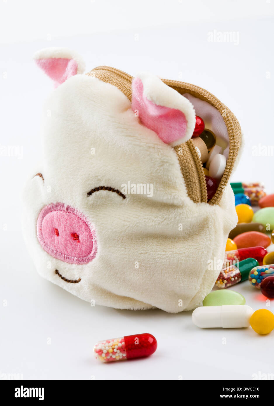Conceptual image of a soft toy pig filled with pills and capsules ...