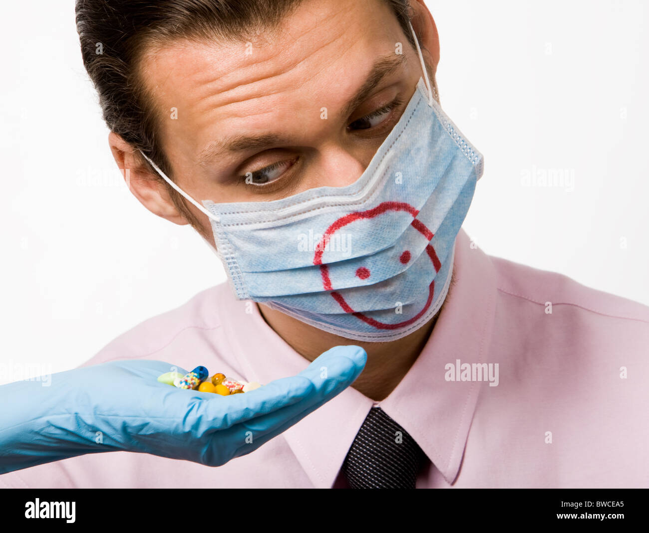 Photo of gloved hand holding pills and man in mask looking at them ...