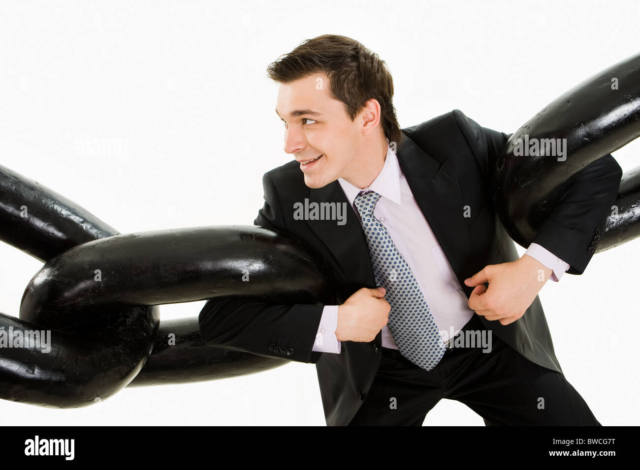 Portrait of powerful businessman holding two sections of huge chain by ...