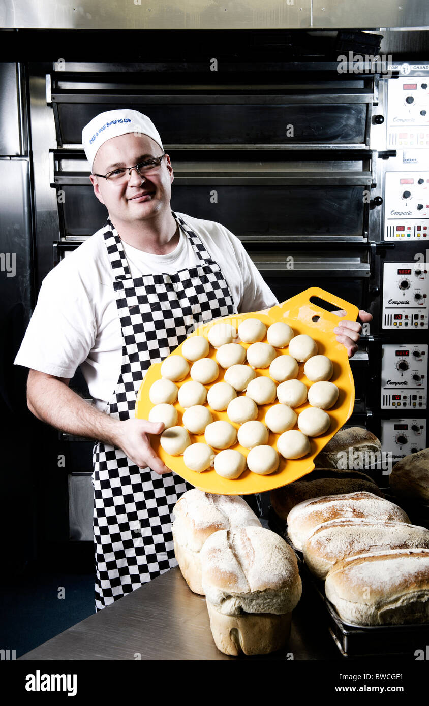 Traditional bakery baker at work with dough rolls ready for proving ...