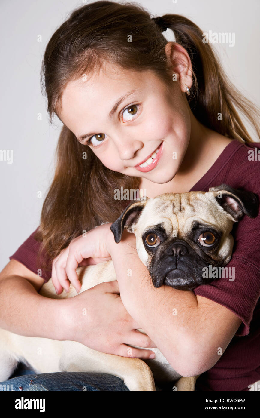 Studio portrait of smiling girl (10-11) holding pug Stock Photo - Alamy