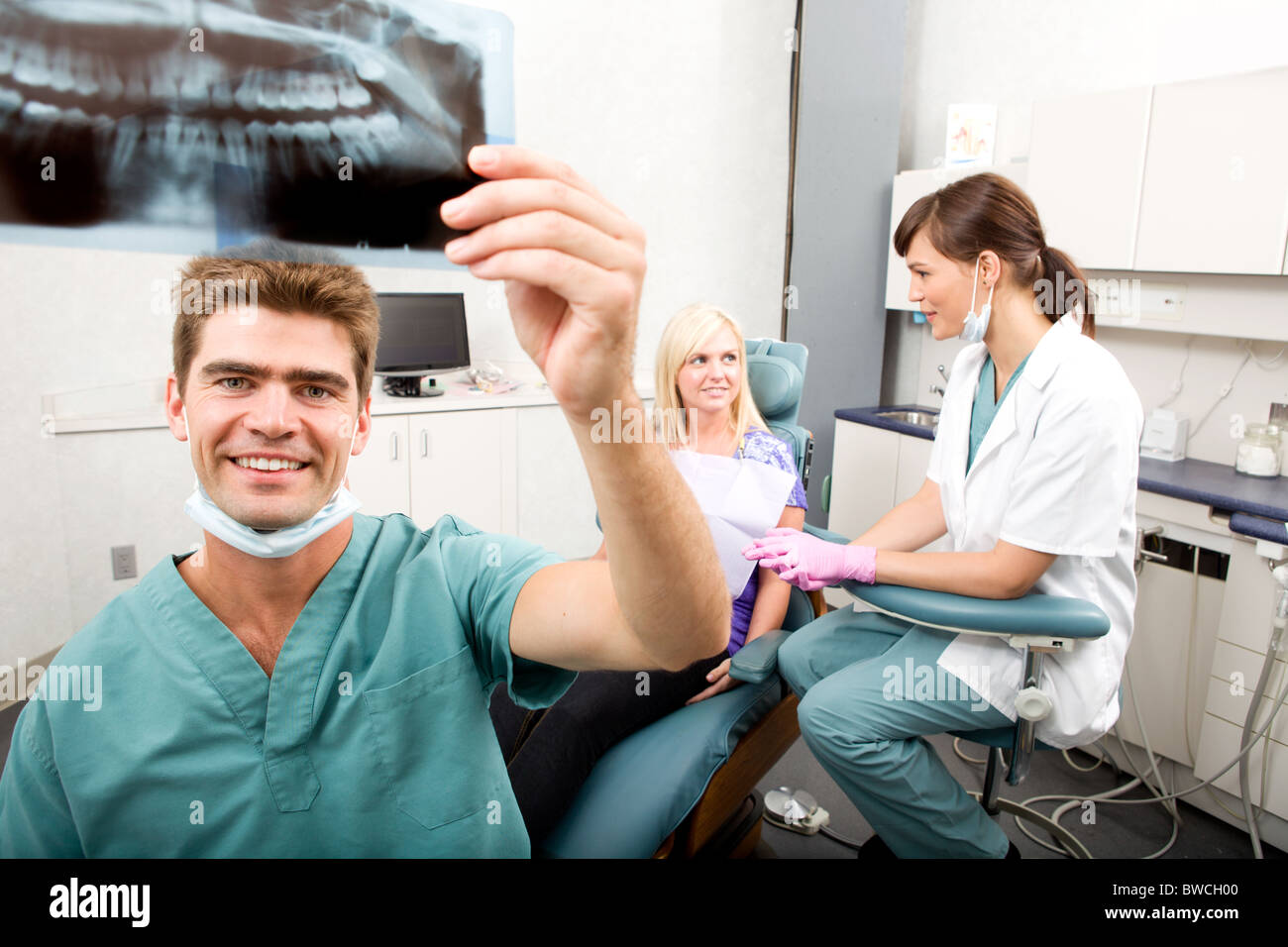 A dentist holding an x-ray while looking and smiling at the camera ...