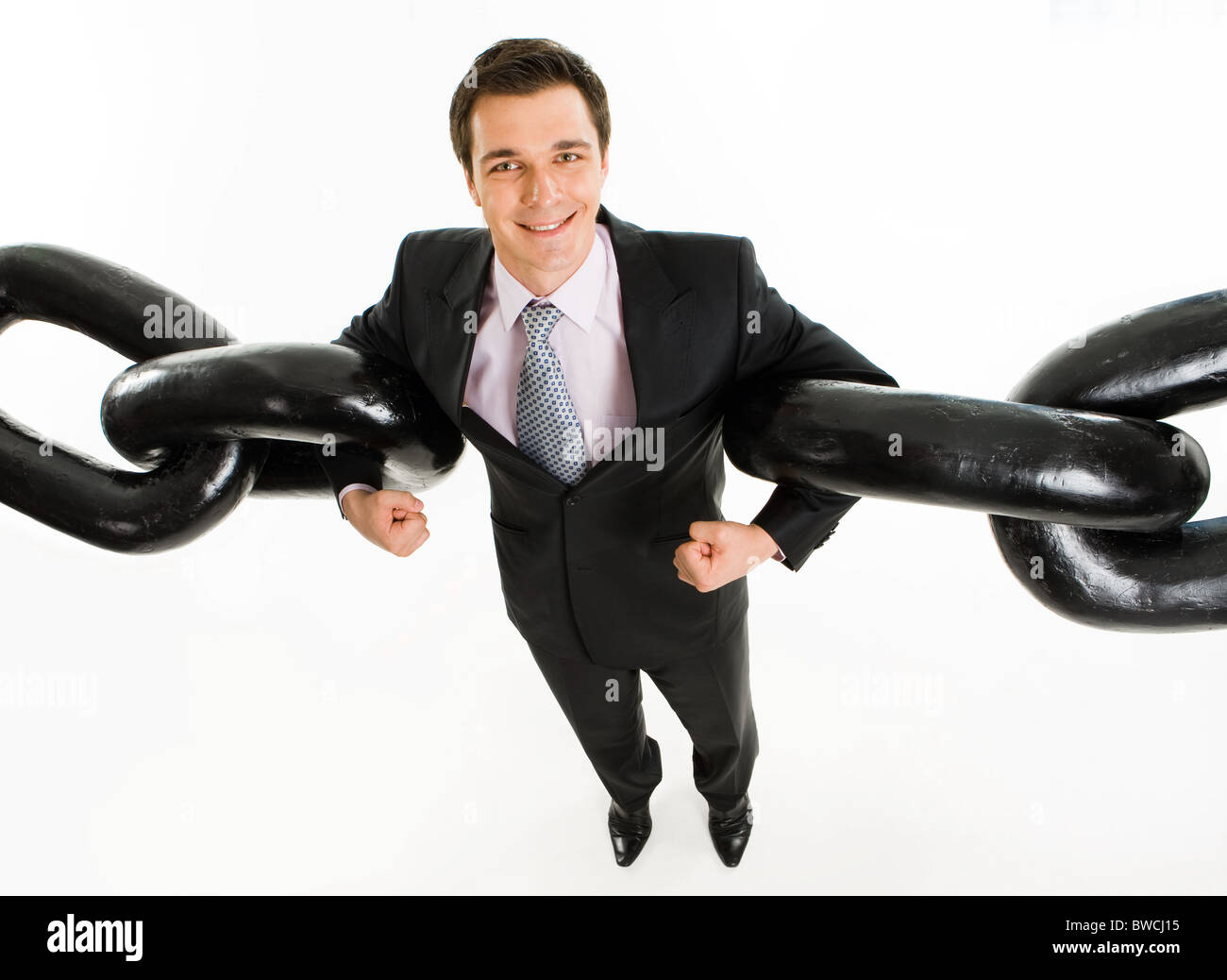 Portrait of powerful businessman holding two sections of huge chain by ...