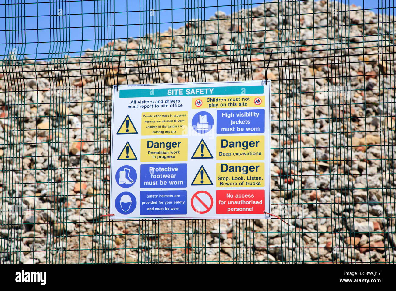 Site Safety sign on wire mesh fence in front of pile of rubble Stock ...