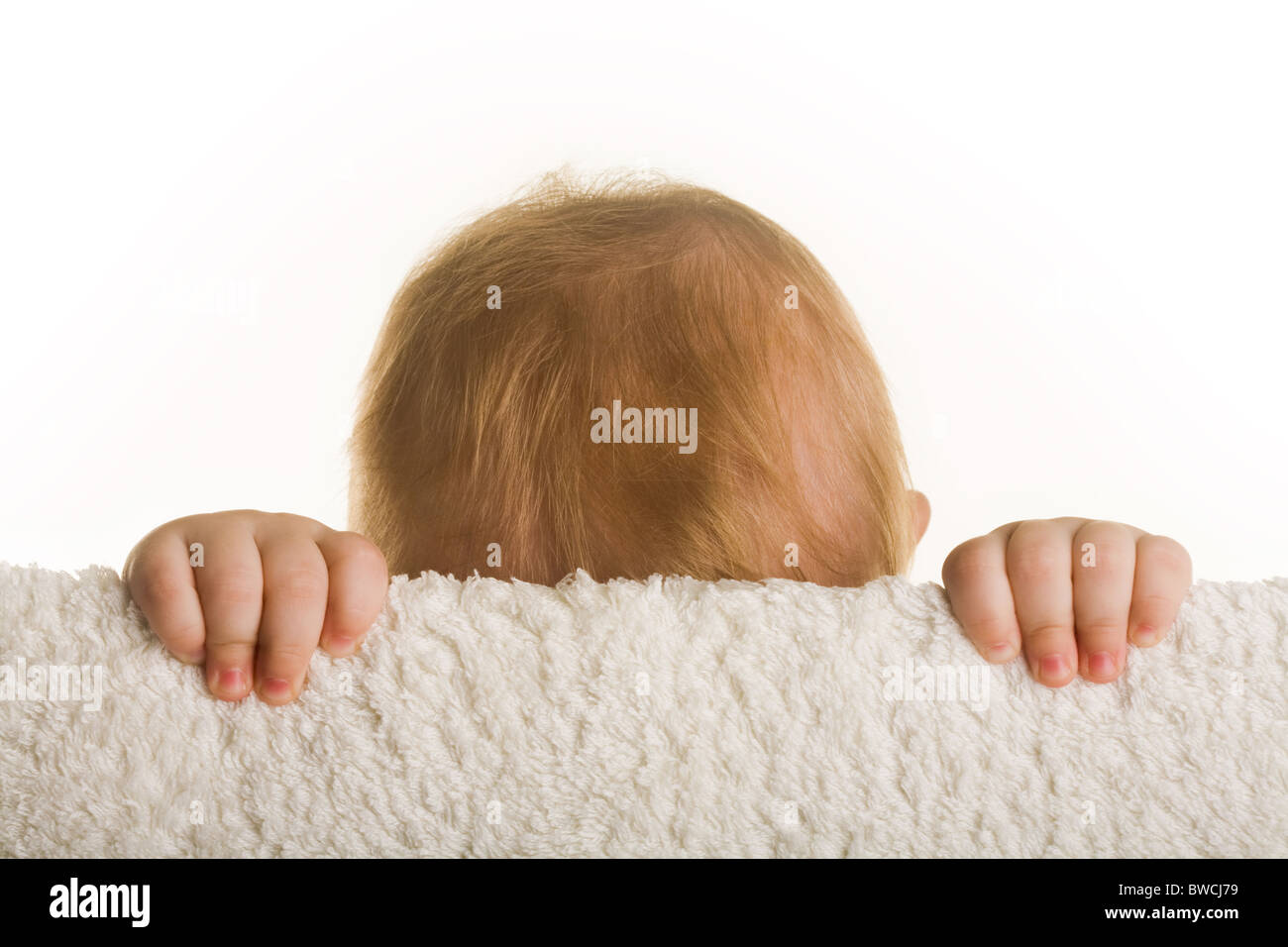 Adorable baby hiding his face behind barrier over white background ...