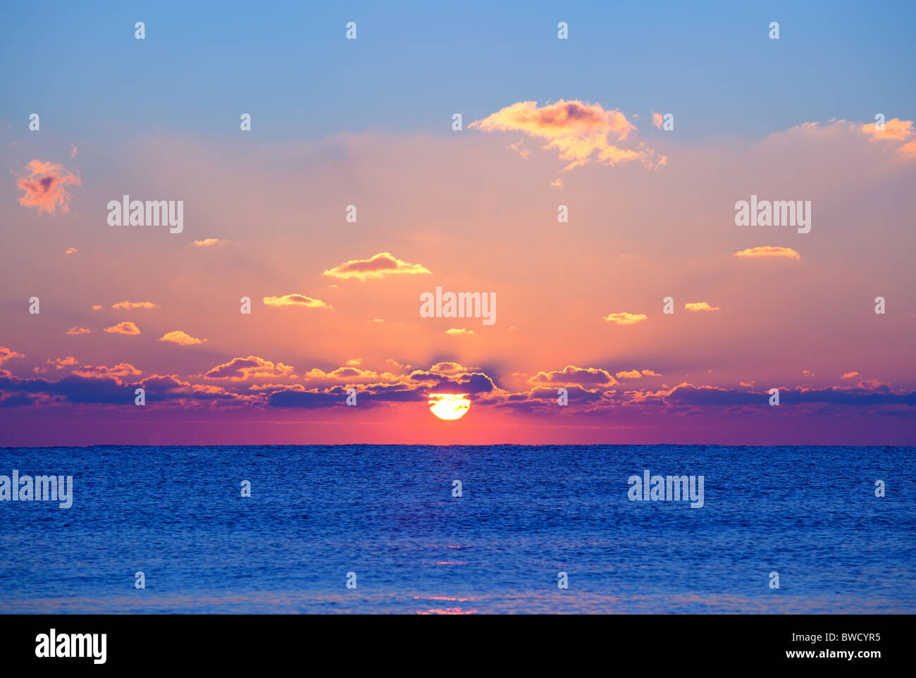 Red rising sun above the dark blue sea Stock Photo - Alamy