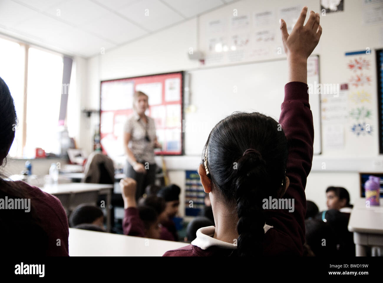 Child putting her hand up to answer a question at school Stock Photo ...