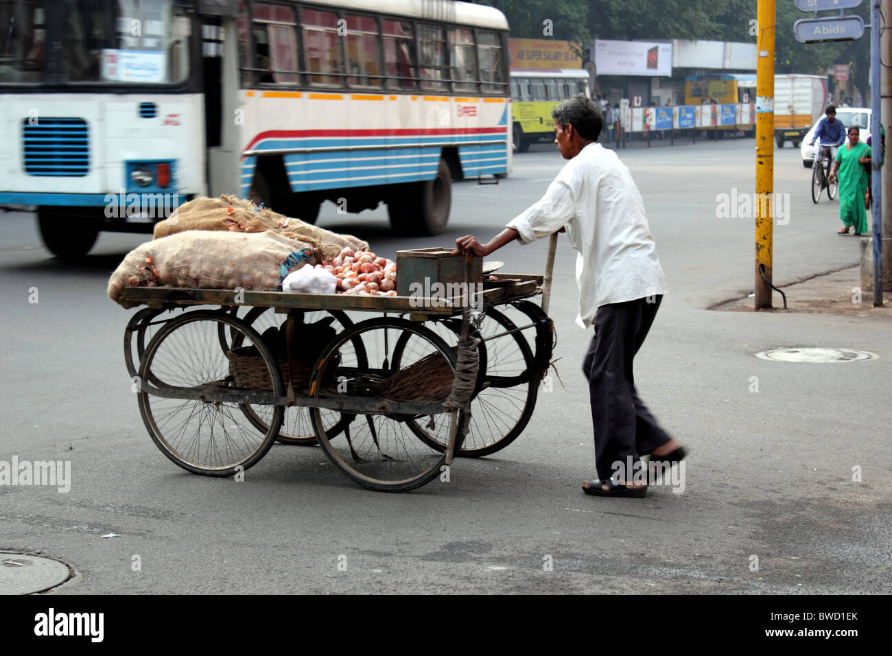 Indian man pushing handcart carrying sacks of fresh vegetables along a ...