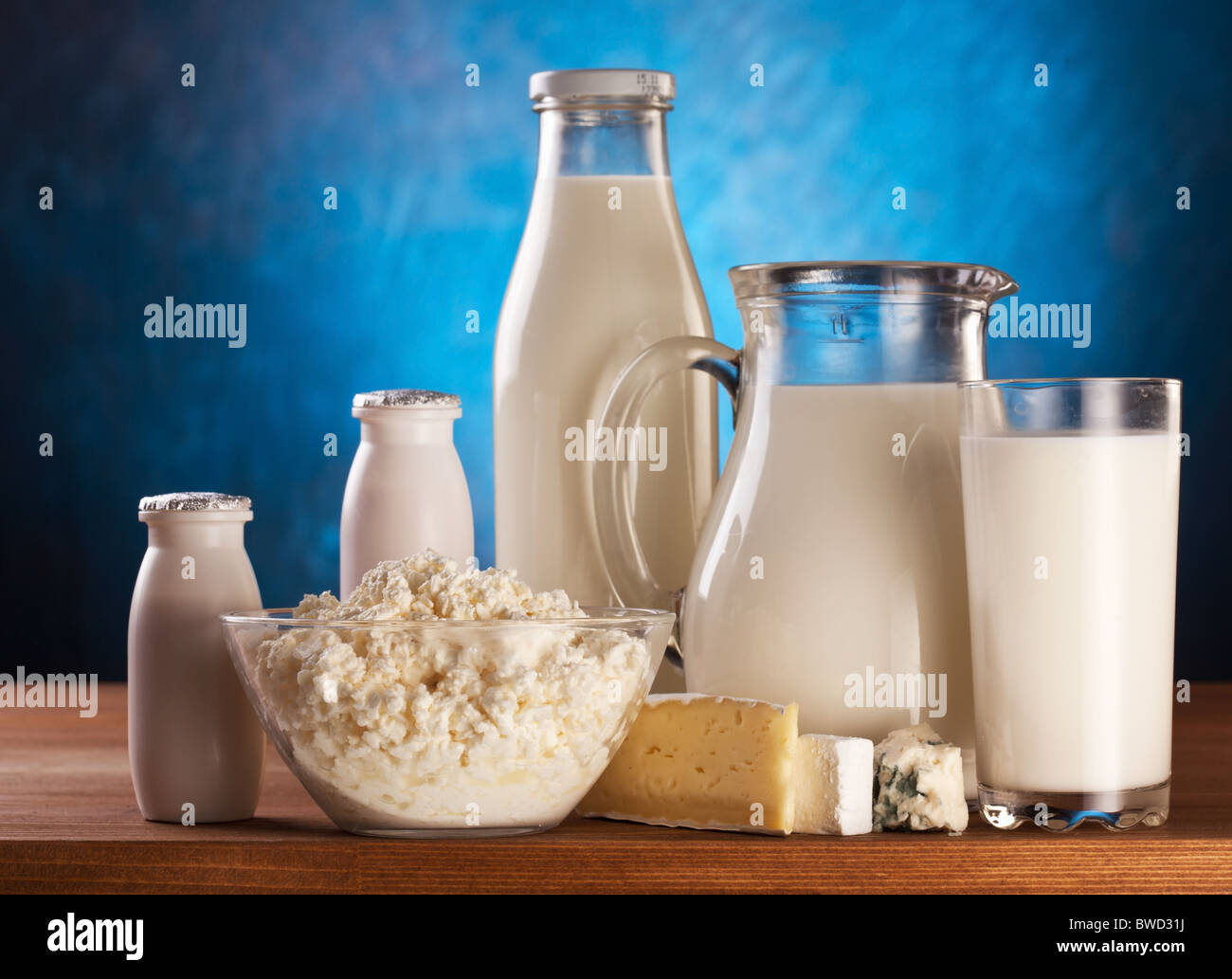 Different milk products: cheese, cream, milk, yoghurt. On a blue ...