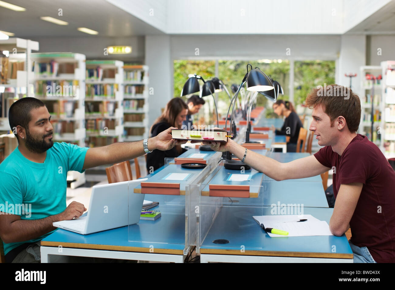 two college students sitting in library with laptop computer and ...