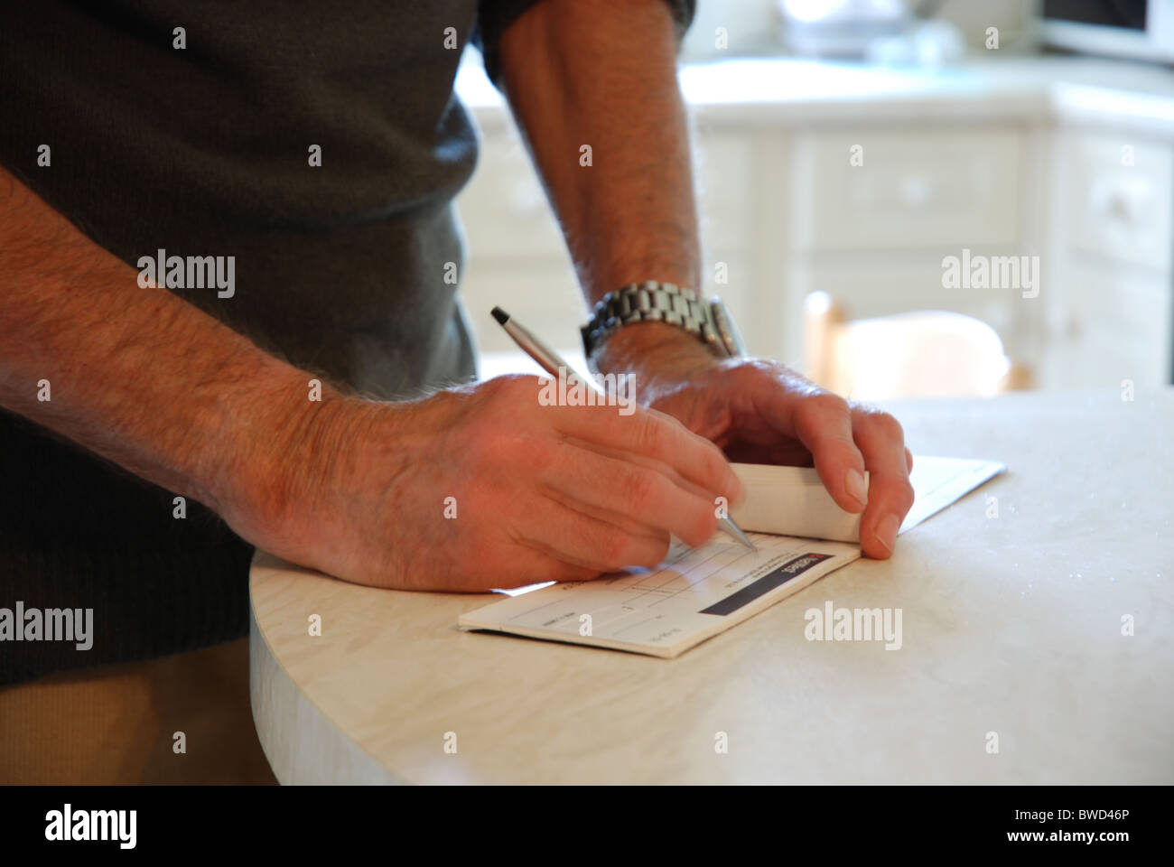 Man writing out a cheque in a cheque book Stock Photo - Alamy